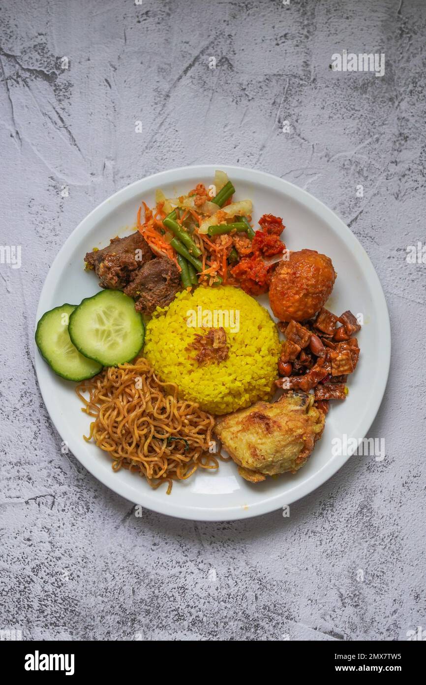 Indonesian traditional food, nasi kuning / yellow turmeric rice served ...