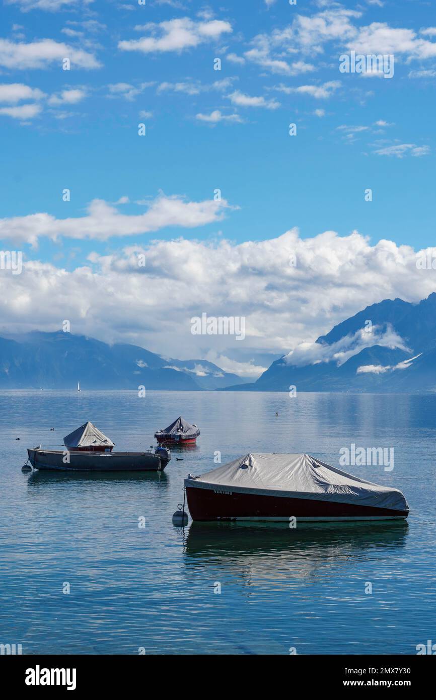 Small covered boats floating in front of distant mountains in lake ...