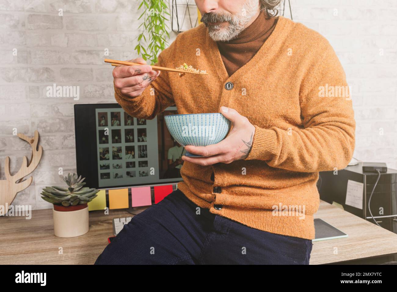 Close-up of freelancer eating oriental food, holding rice with ...
