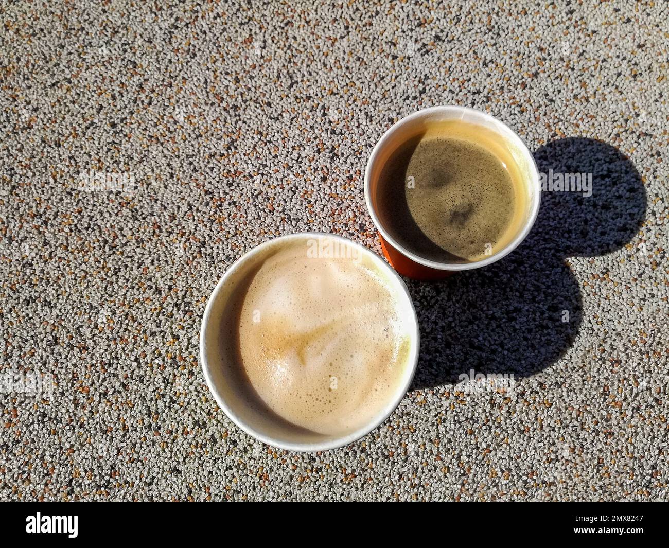Two disposable portable paper cups of different sizes with coffee cast ...