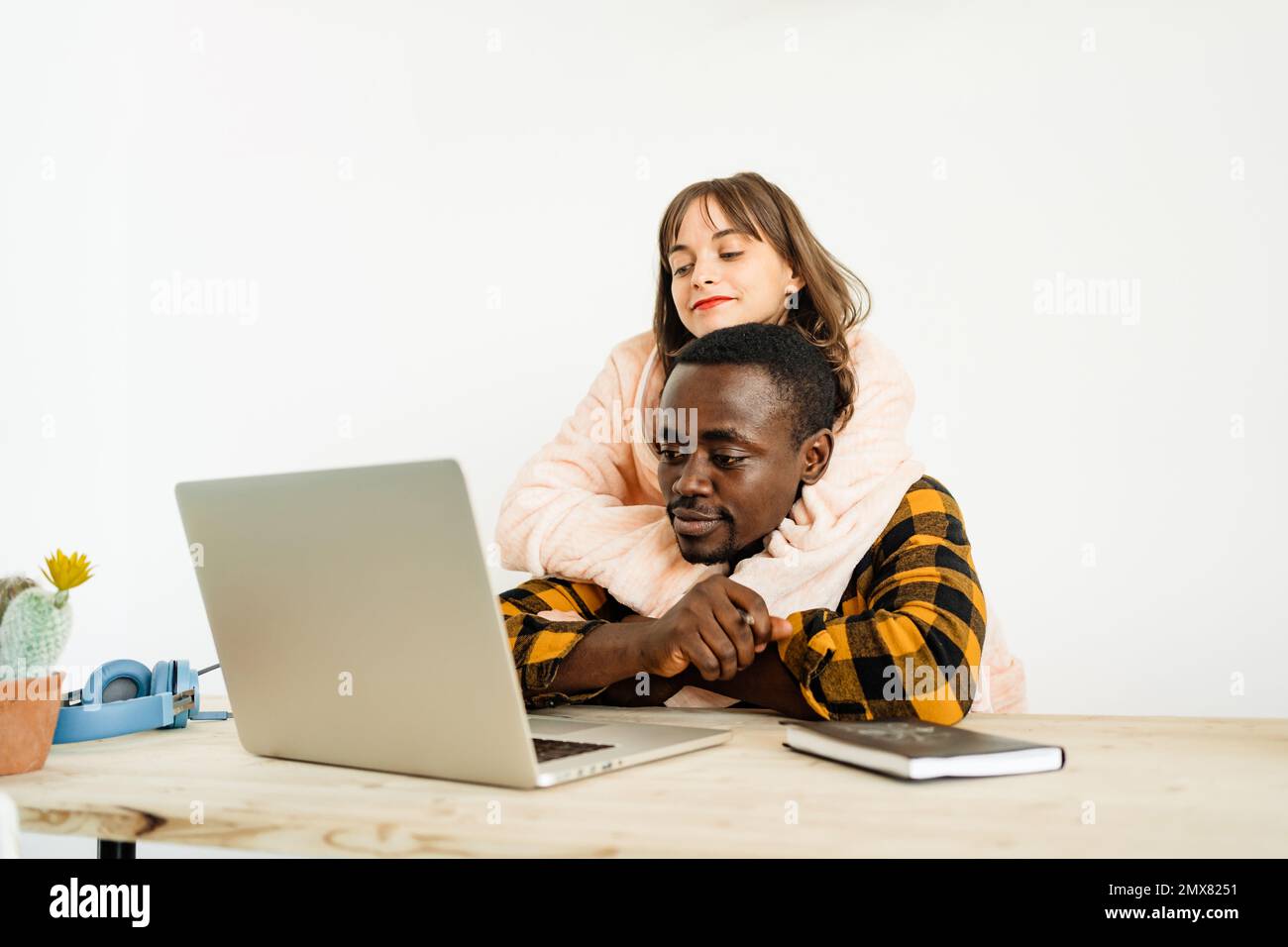 Happy woman in casual clothes hugging African American man taking notes ...