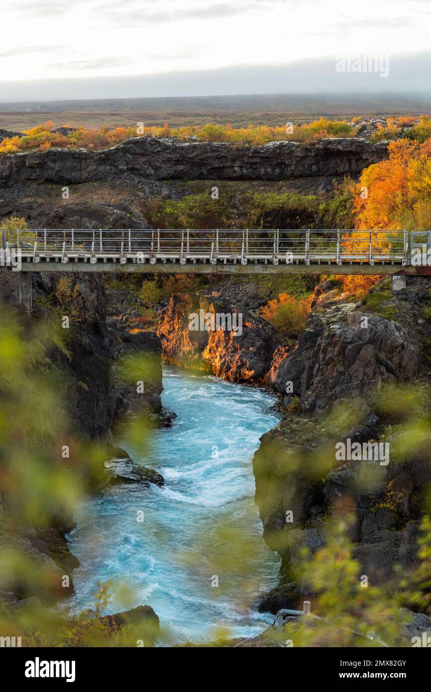 Scenic landscape of metal footbridge over fast river flowing between ...