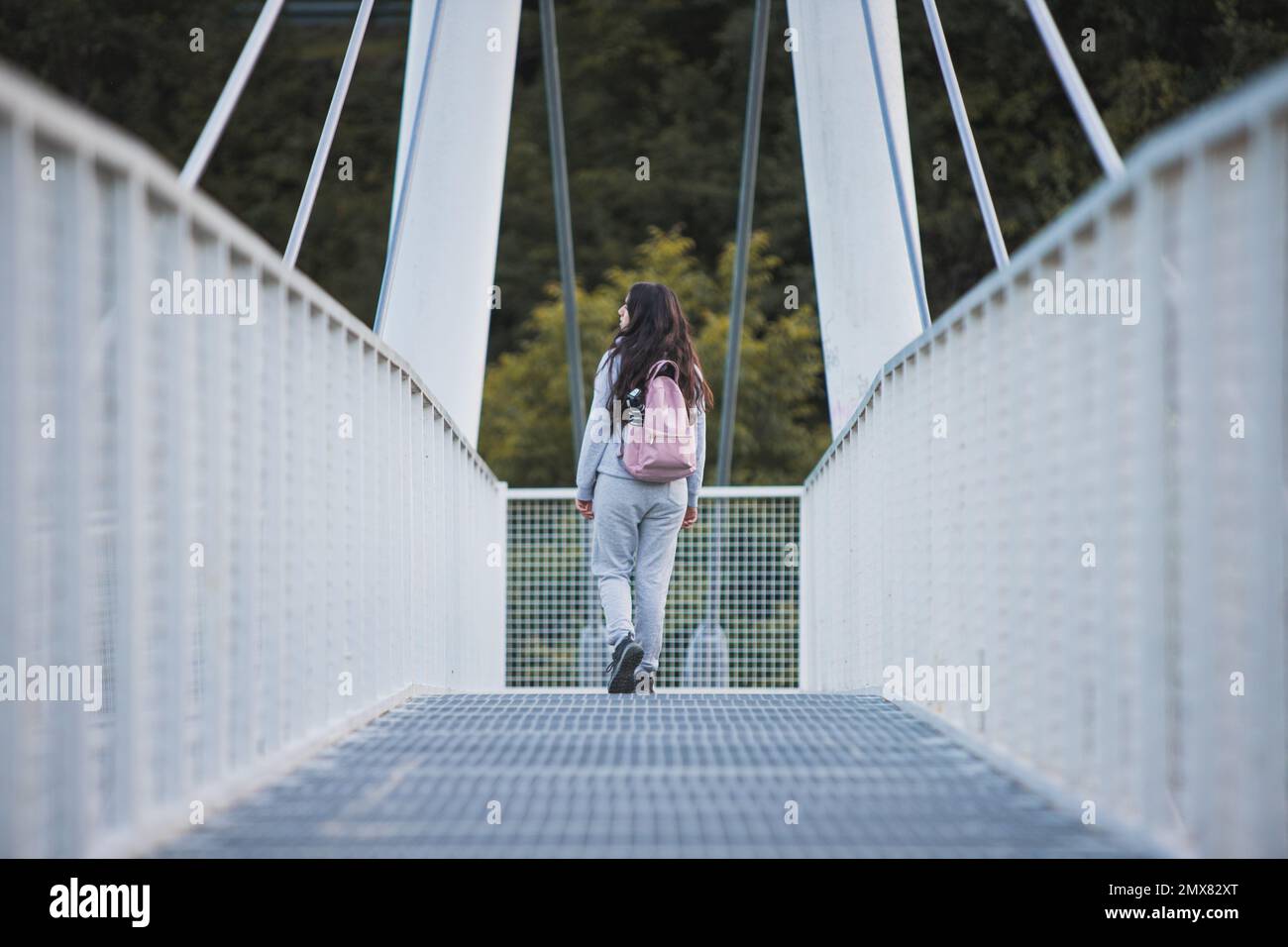 Back view of anonymous female in casual clothes with backpack walking ...