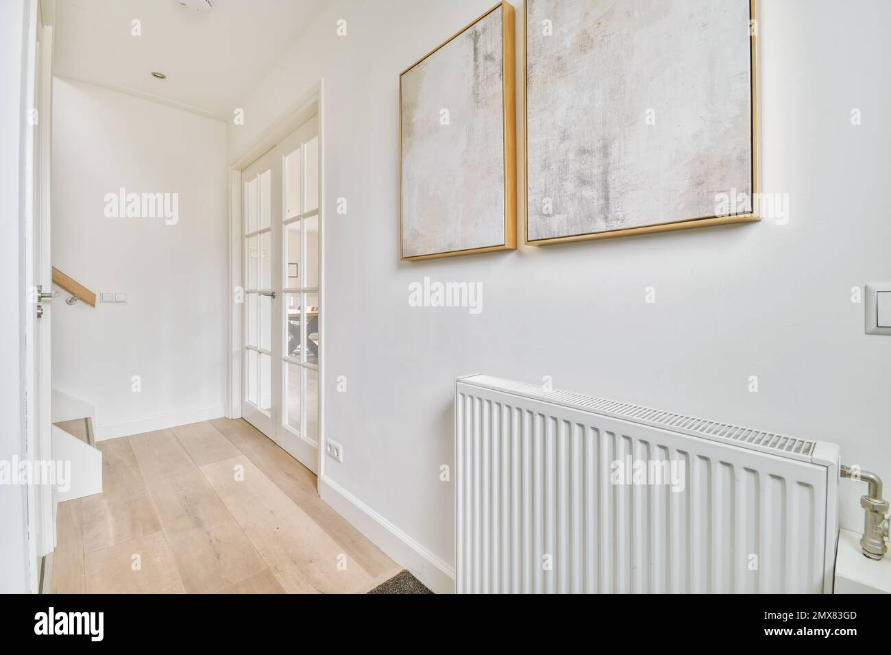Interior design of hallway with radiator placed under pictures on white ...