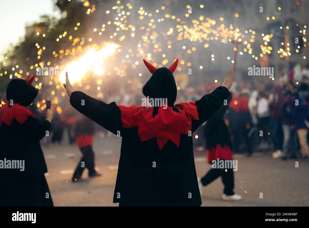 Back view of anonymous person in costume with horns and stick standing ...