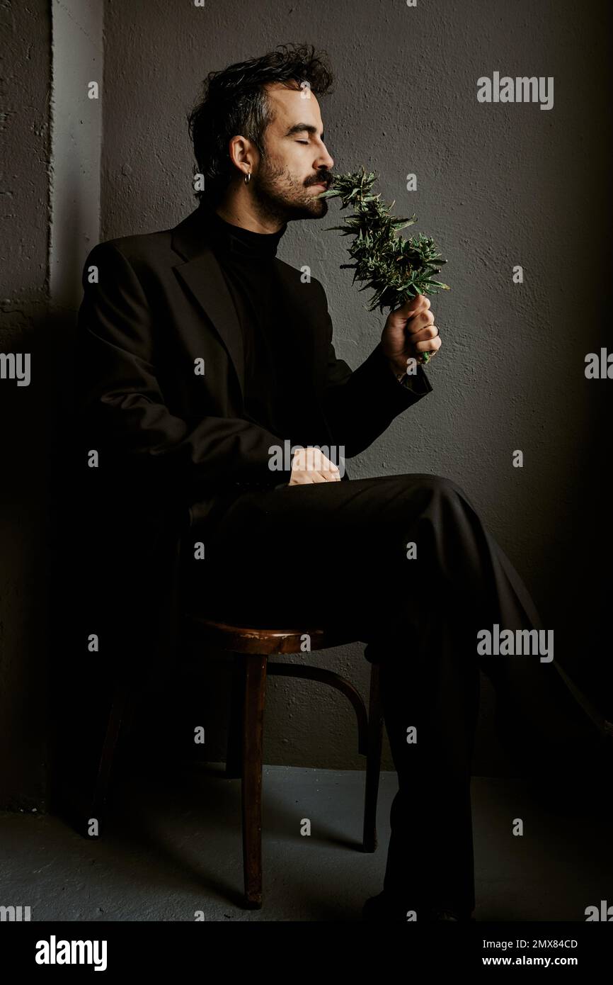 Side view of bearded male in black elegant suit sitting with crossed ...