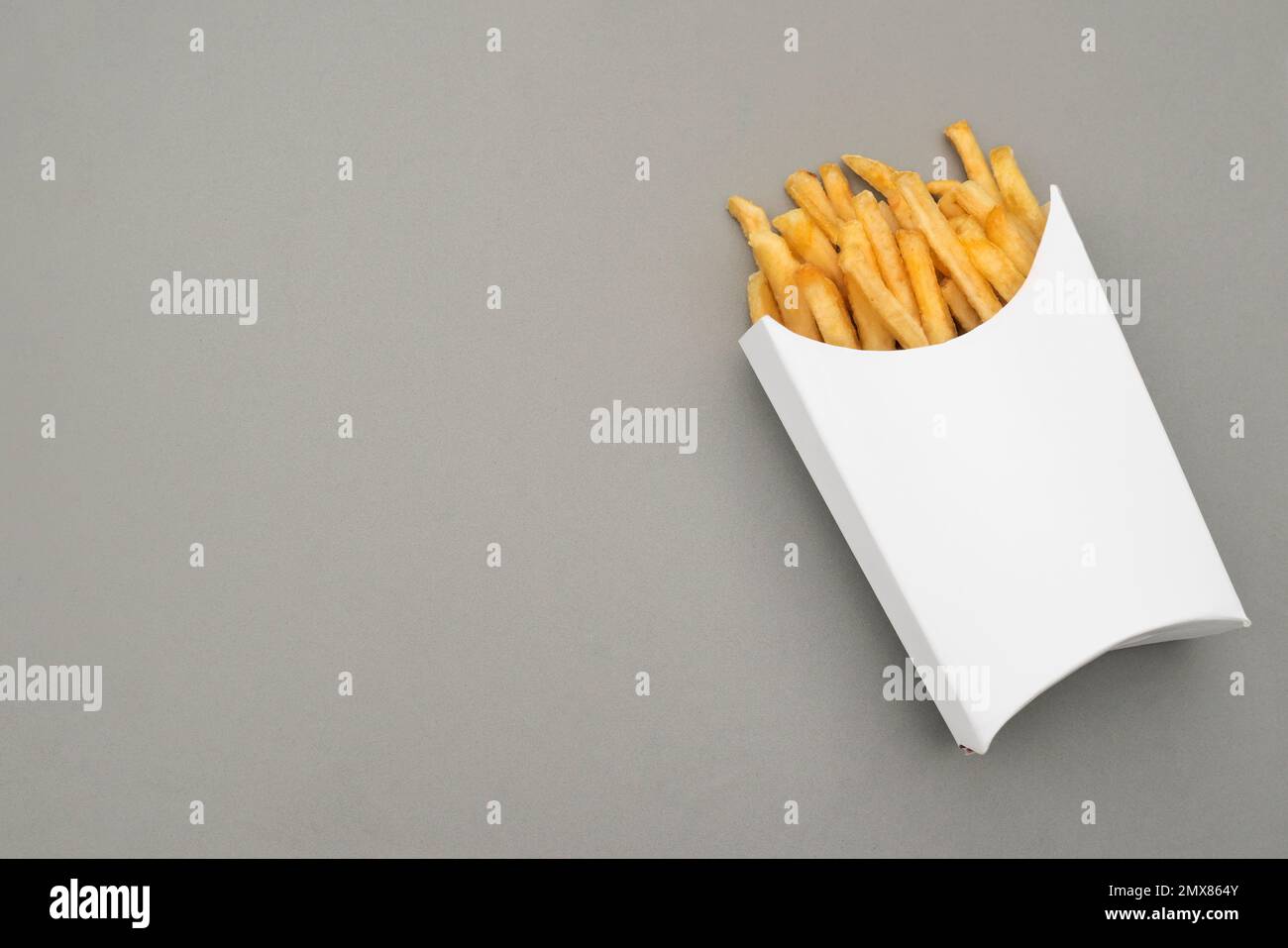 A portion french fries in a grey cardboard box. Grey paper background ...