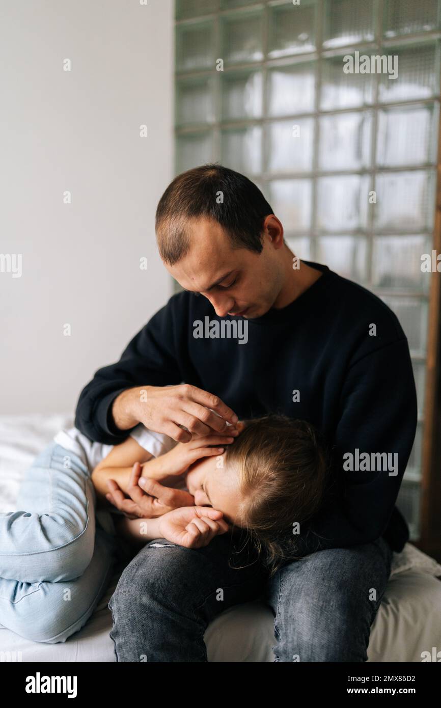 Vertical portrait of loving caring young father comforting crying sad ...