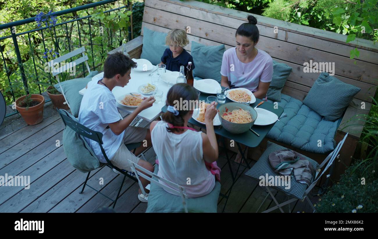 Family eating lunch in home backyard wooden patio. Top view of people ...