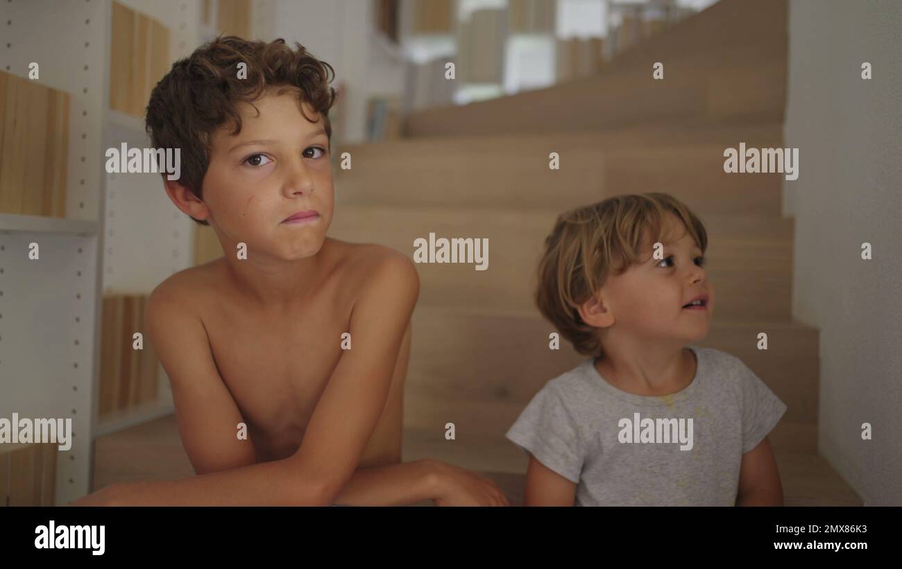 Cute small brothers hanging out together at home stairs. Older sibling ...