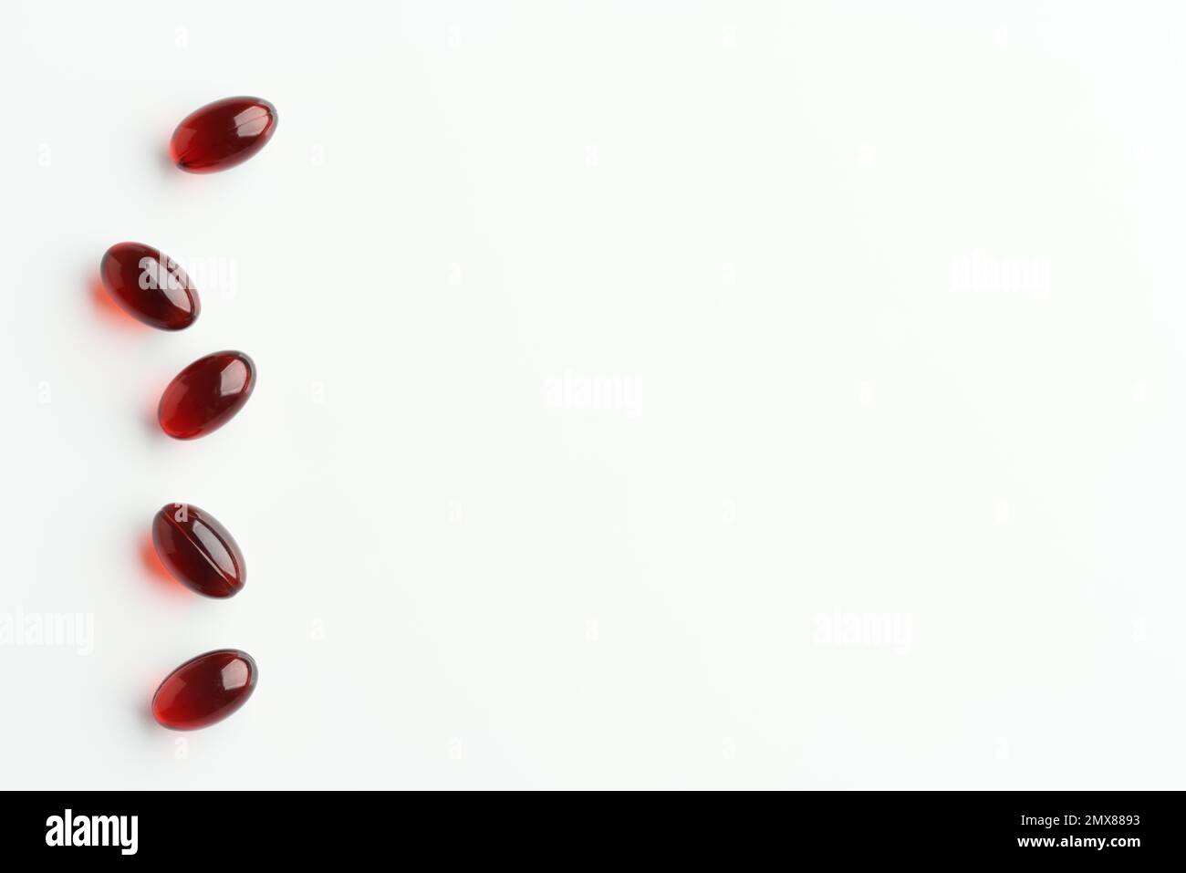 Red krill oil pills or globules on white background with copy space ...