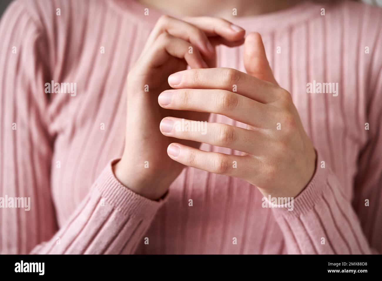 Teenage girl in pink top tapping on the side of the hand acupressure ...
