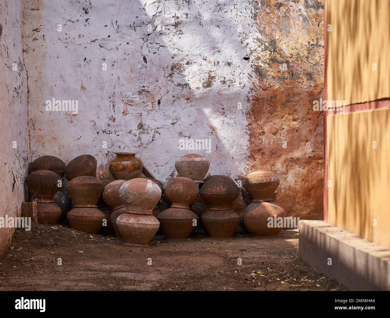 Ancient clay pots stacked against a rustic, textured wall Stock Photo ...