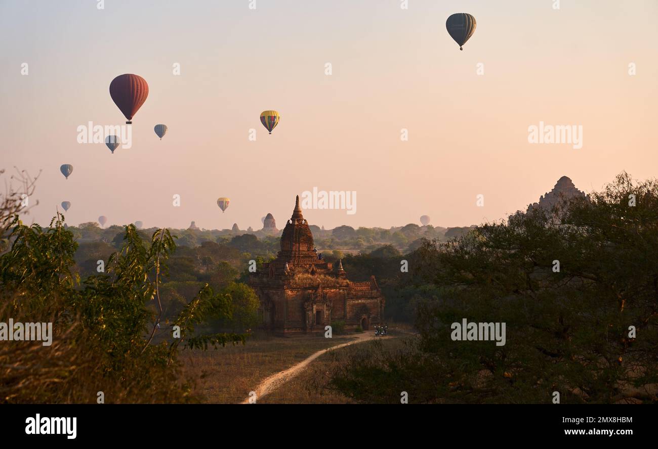 Hot air balloons rising over an ancient Shan temple at sunrise in Bagan ...
