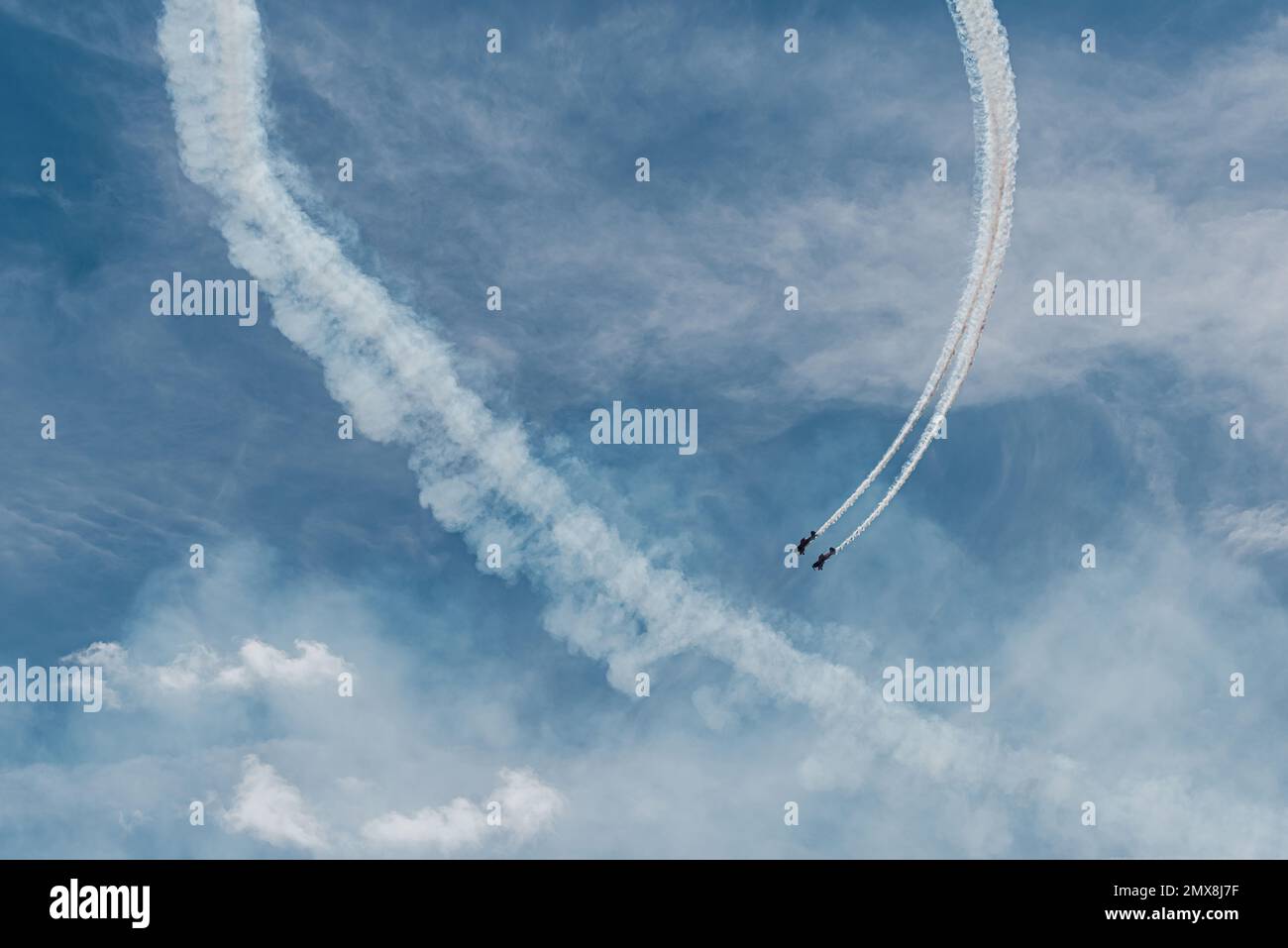 two small planes fly in parallel describing a white parabolic ...