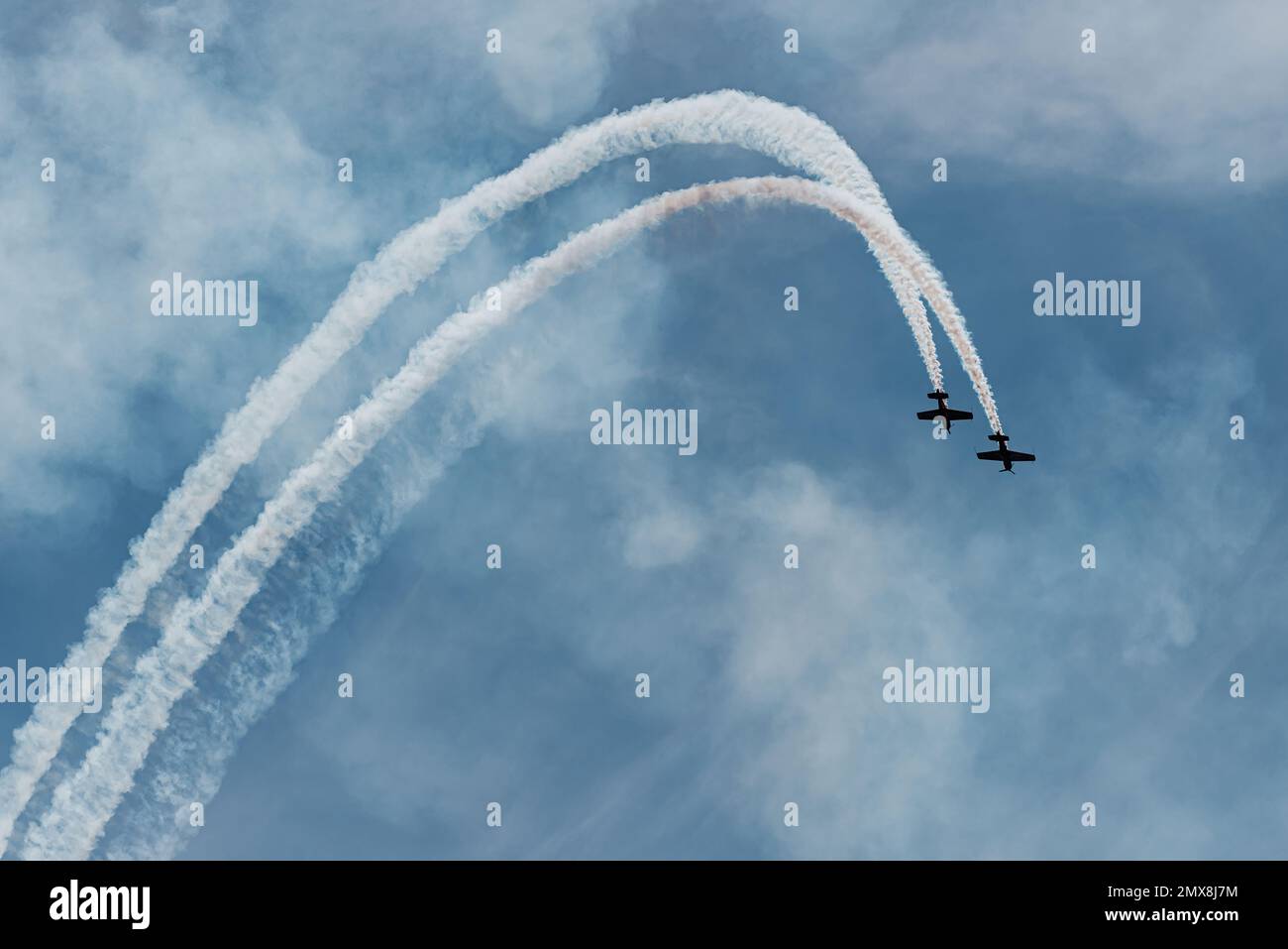 two small planes fly in parallel describing a white trajectory over the ...
