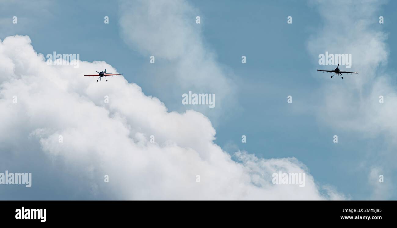 two planes flying head-on over a sky blue sky with white clouds ...