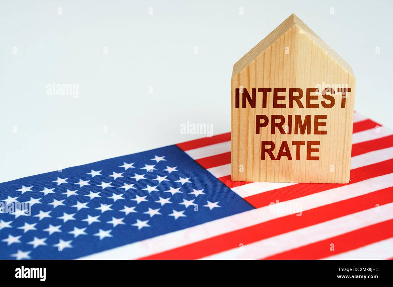 Real estate concept. On the US flag is a model of a wooden house with ...