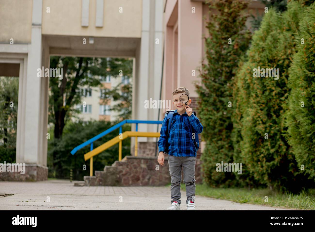 Schoolboy looking through a magnifying glass, with a surprised ...