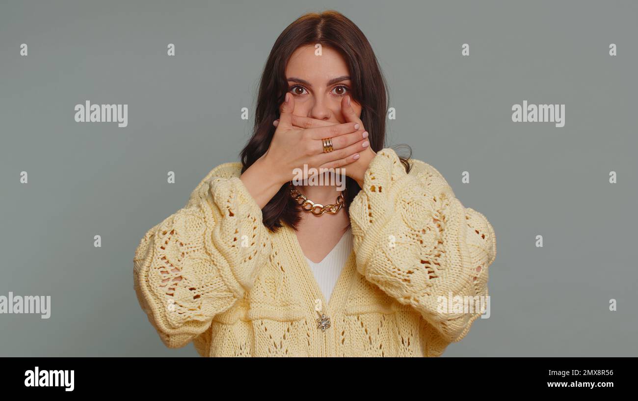 I will not say anyone. Frightened woman closing her mouth with hand ...