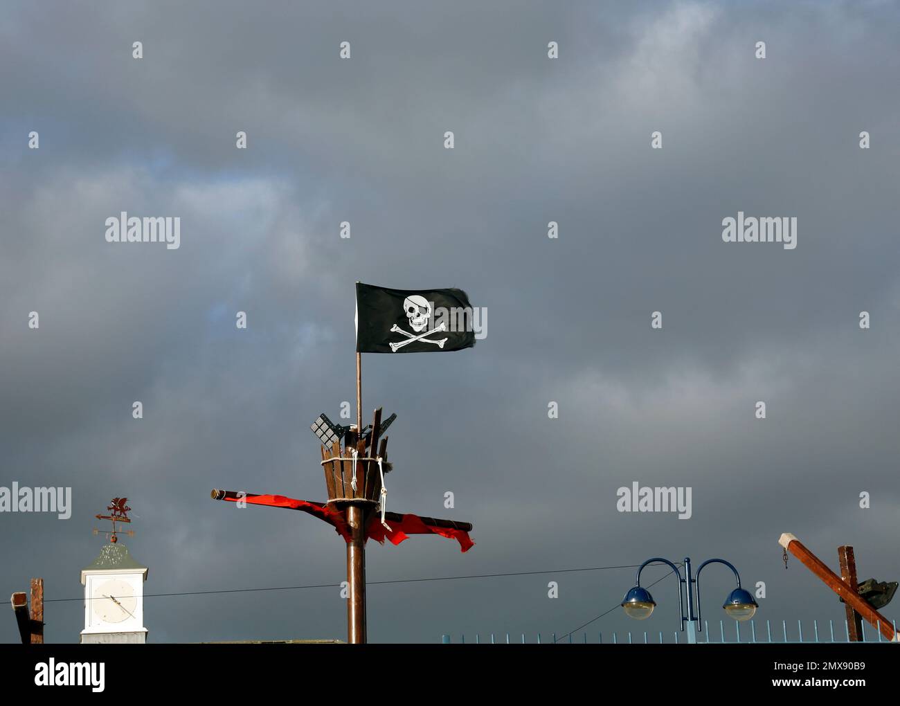 Jolly Roger, pirate flag and crow's nest on a mast against a cloudy sky ...