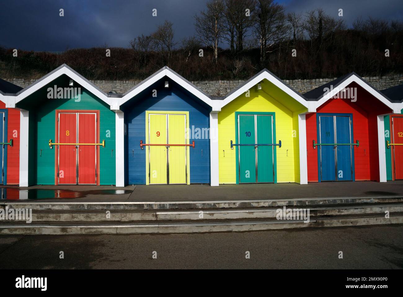 Colourful brightly painted wooden beach huts at Barry Island, locked up out of season. January ...