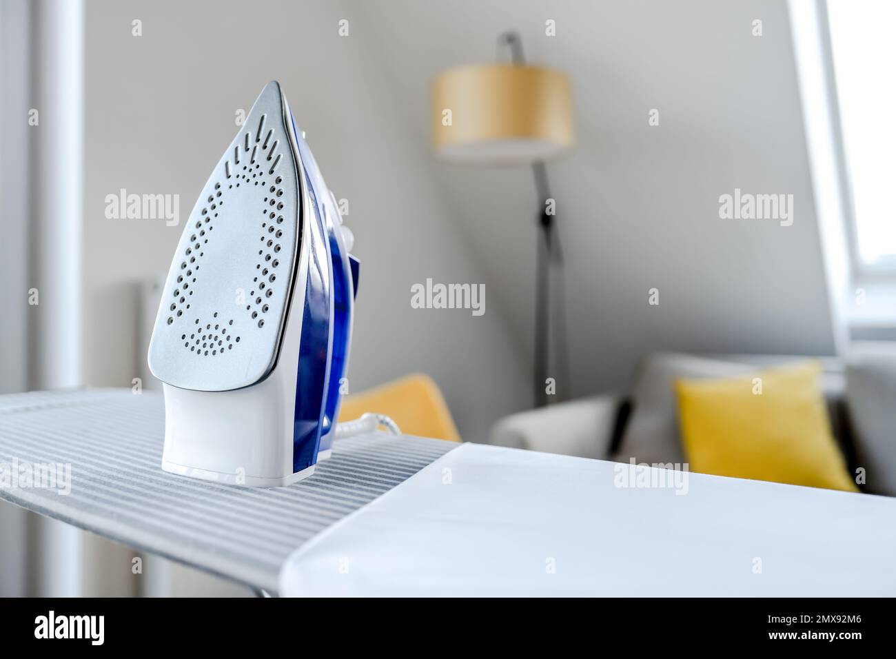 Electrical iron for wrinkled clothes on ironing board indoor. Modern ...