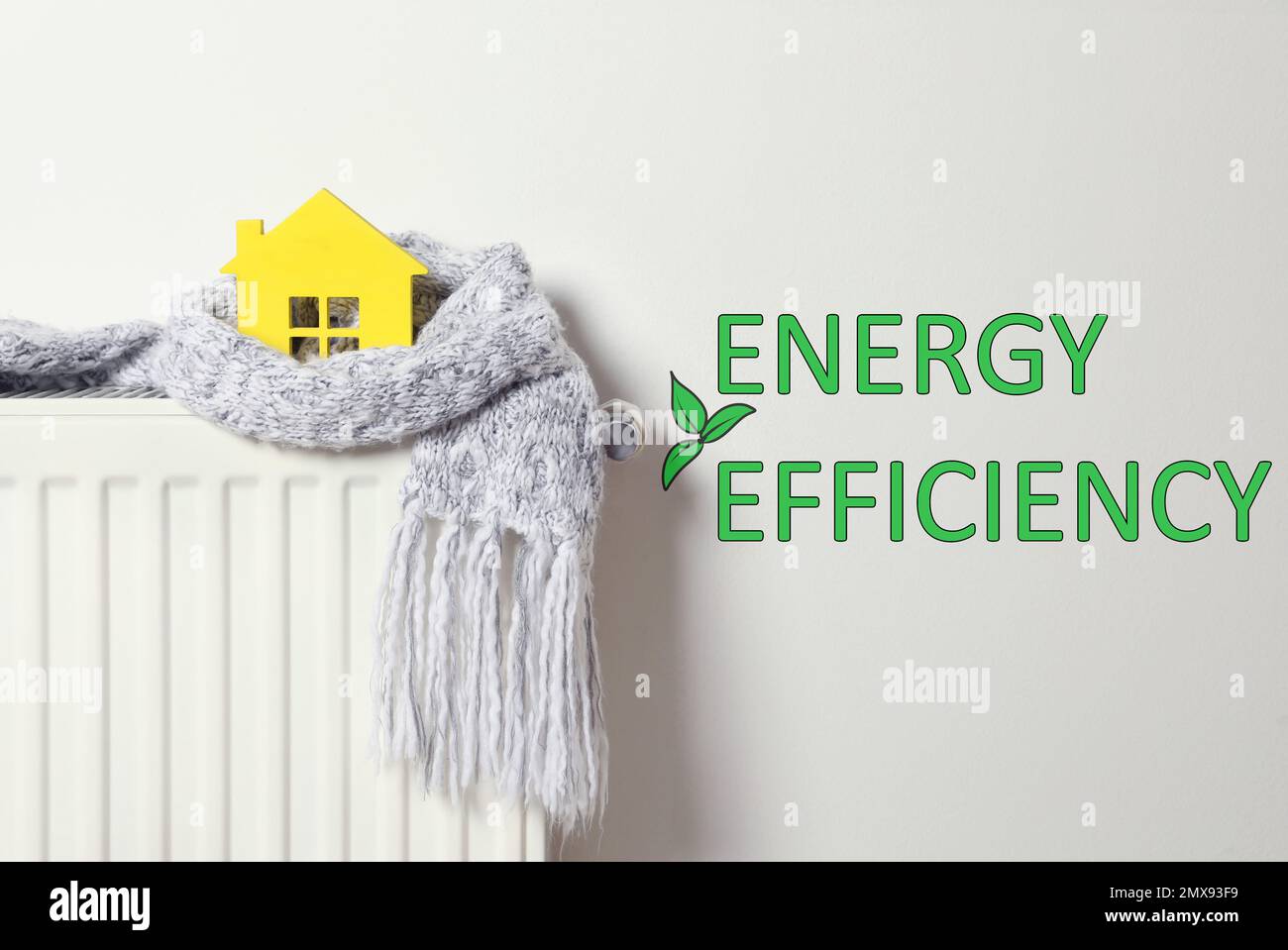 Energy efficiency concept. House model wrapped in scarf on radiator ...