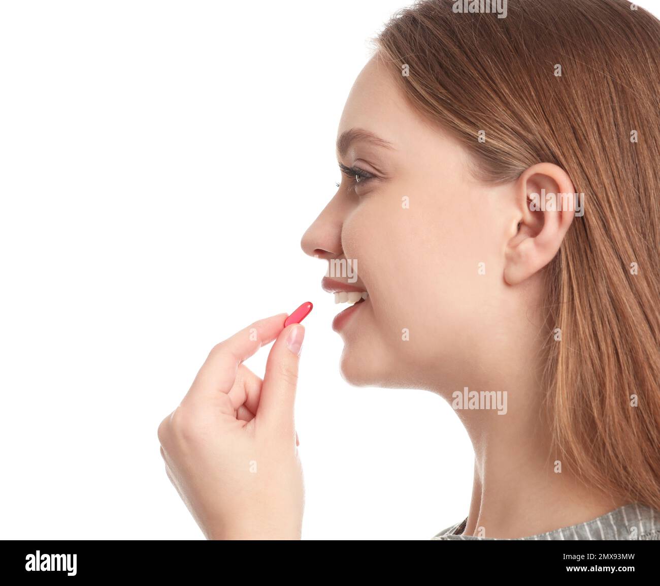 Young woman taking vitamin capsule on white background Stock Photo - Alamy