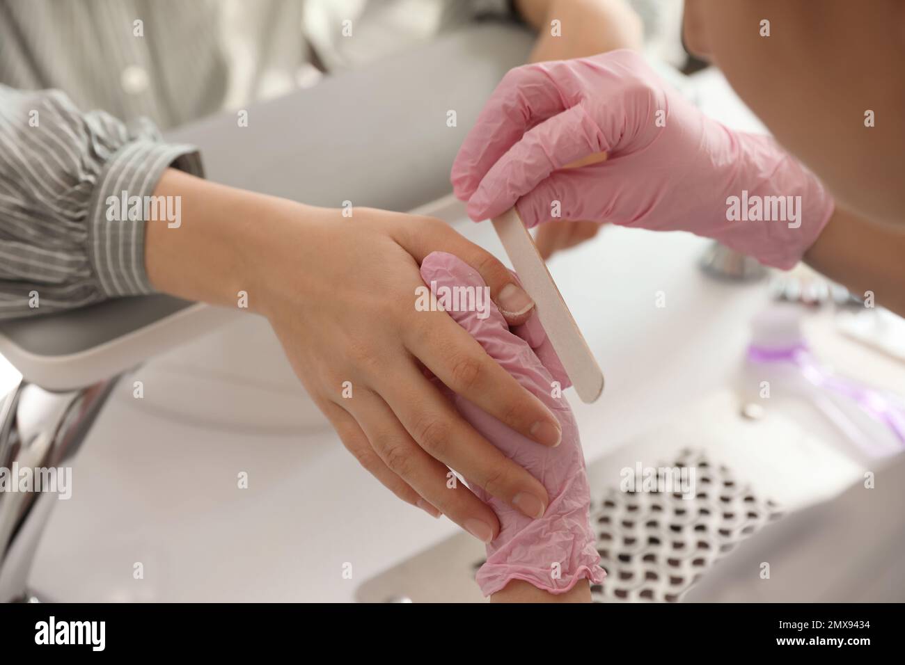 Professional manicurist filing client's nails in beauty salon, closeup ...