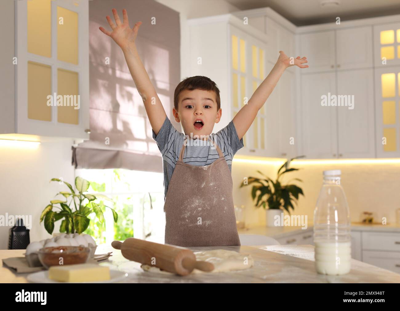 Emotional little boy at table with cooking ingredients in kitchen Stock ...