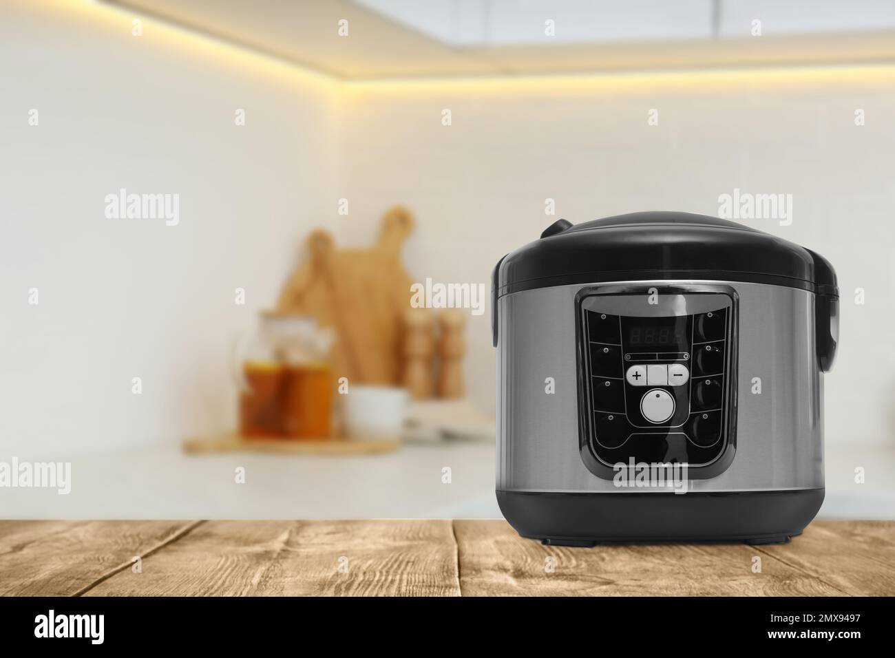 Modern electric multi cooker on wooden table in kitchen. Space for ...