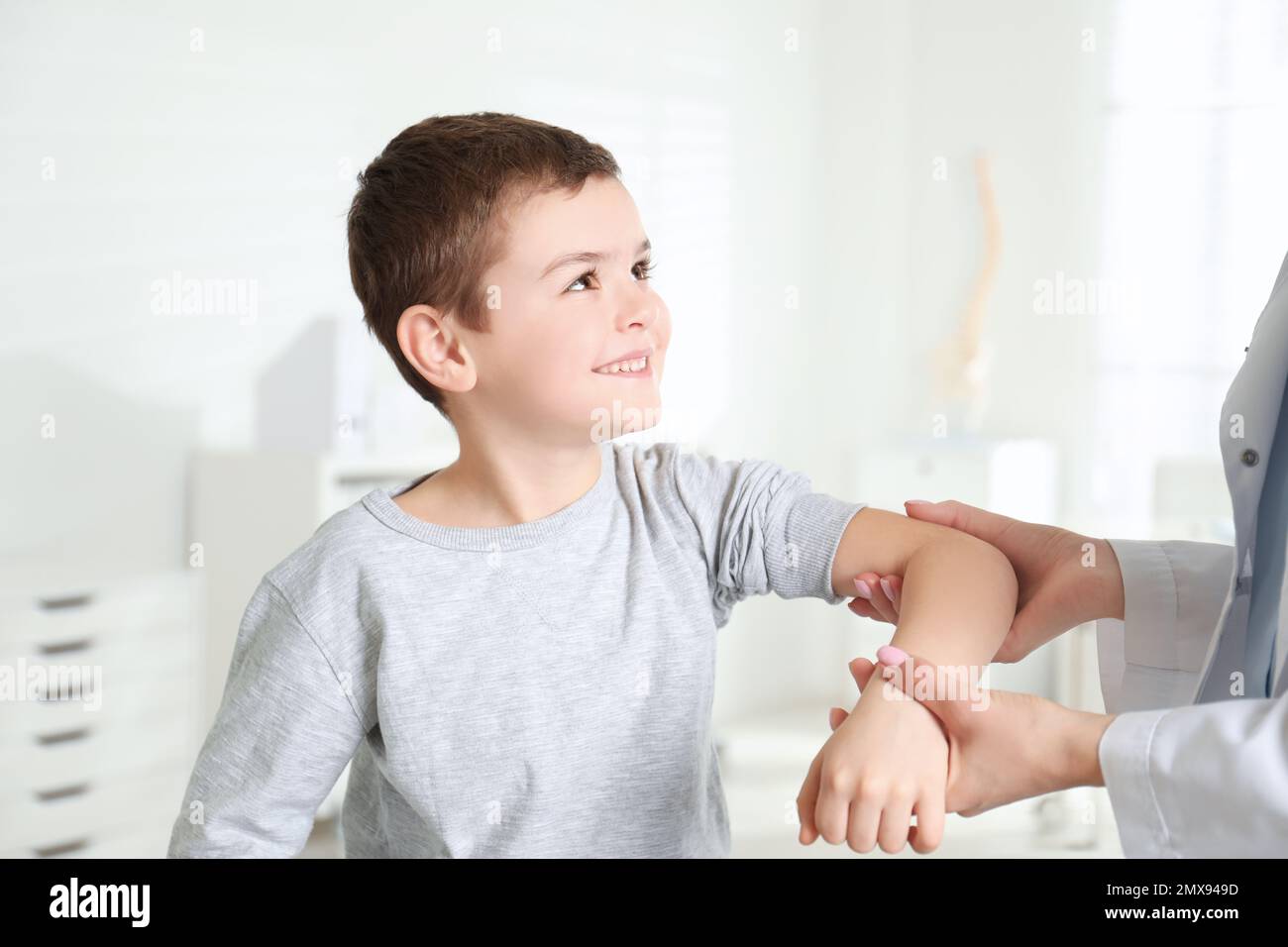Professional orthopedist examining little patient's arm in clinic Stock ...