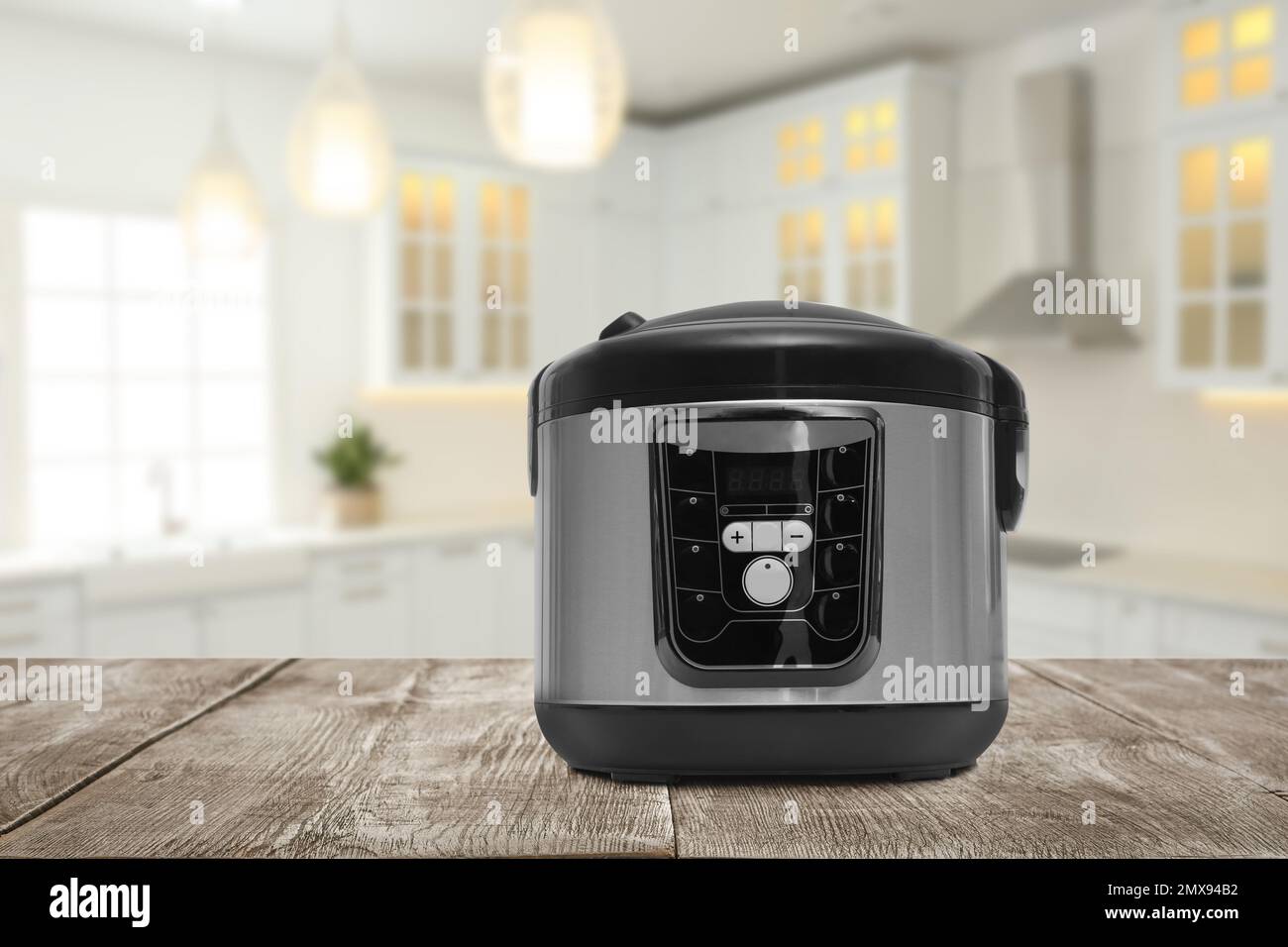 Modern electric multi cooker on wooden table in kitchen. Space for ...
