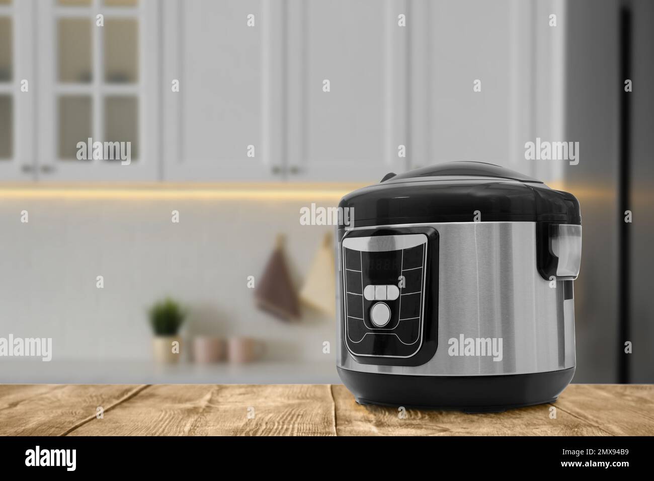 Modern electric multi cooker on wooden table in kitchen. Space for ...