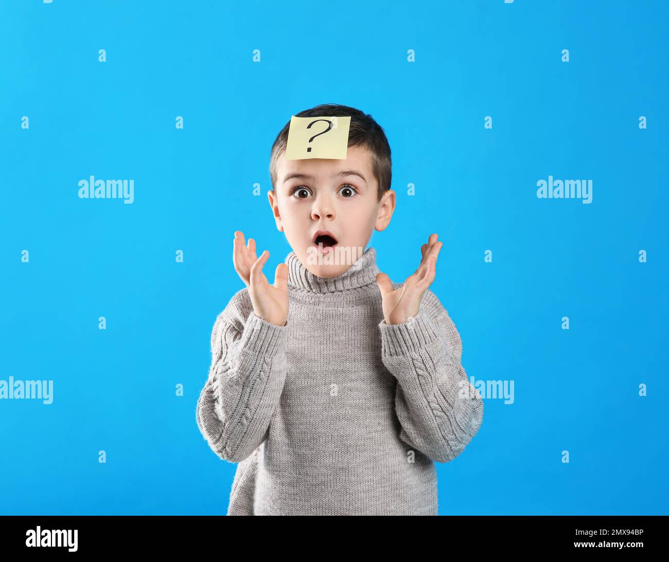 Emotional little boy with question mark on light blue background Stock ...