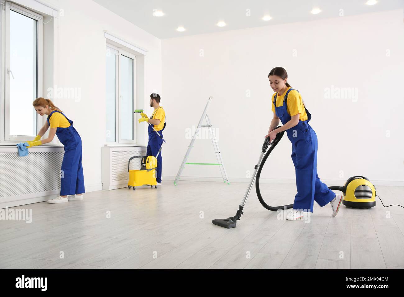 Team of professional janitors in uniforms cleaning room Stock Photo - Alamy