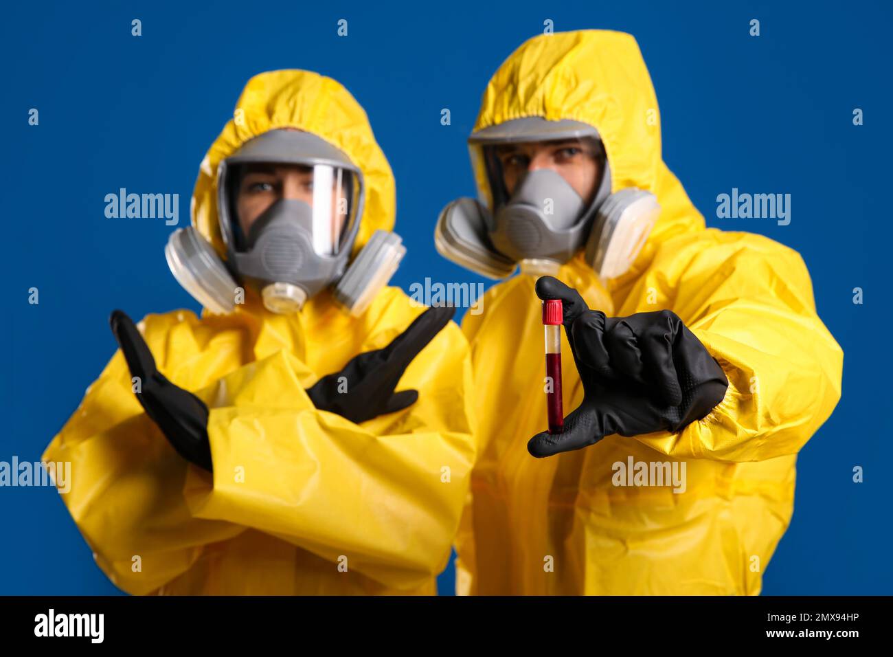 Man and woman in chemical protective suits with test tube of blood ...