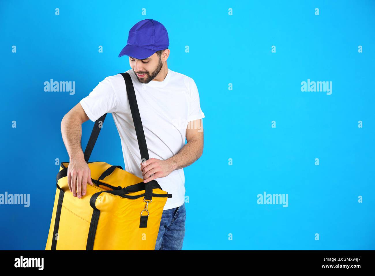 Courier with thermo bag on light blue background, space for text. Food ...