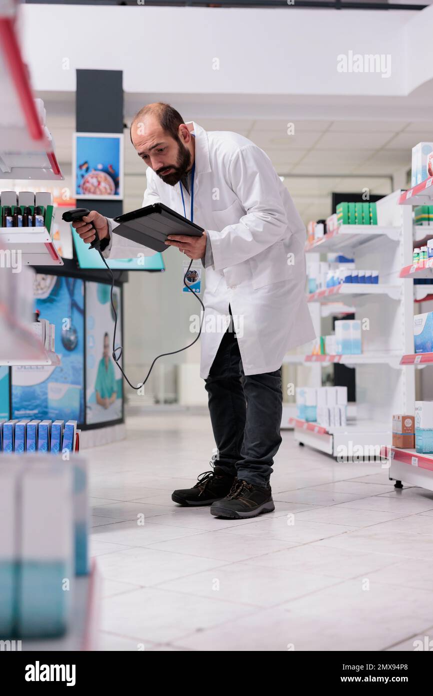 Pharmacist looking at medical pills information on tablet computer ...