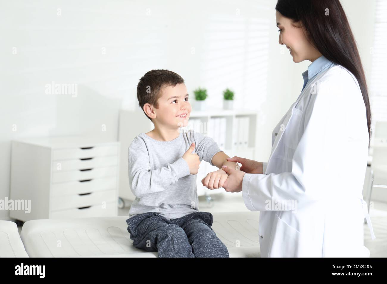 Professional orthopedist examining little patient's arm in clinic Stock ...