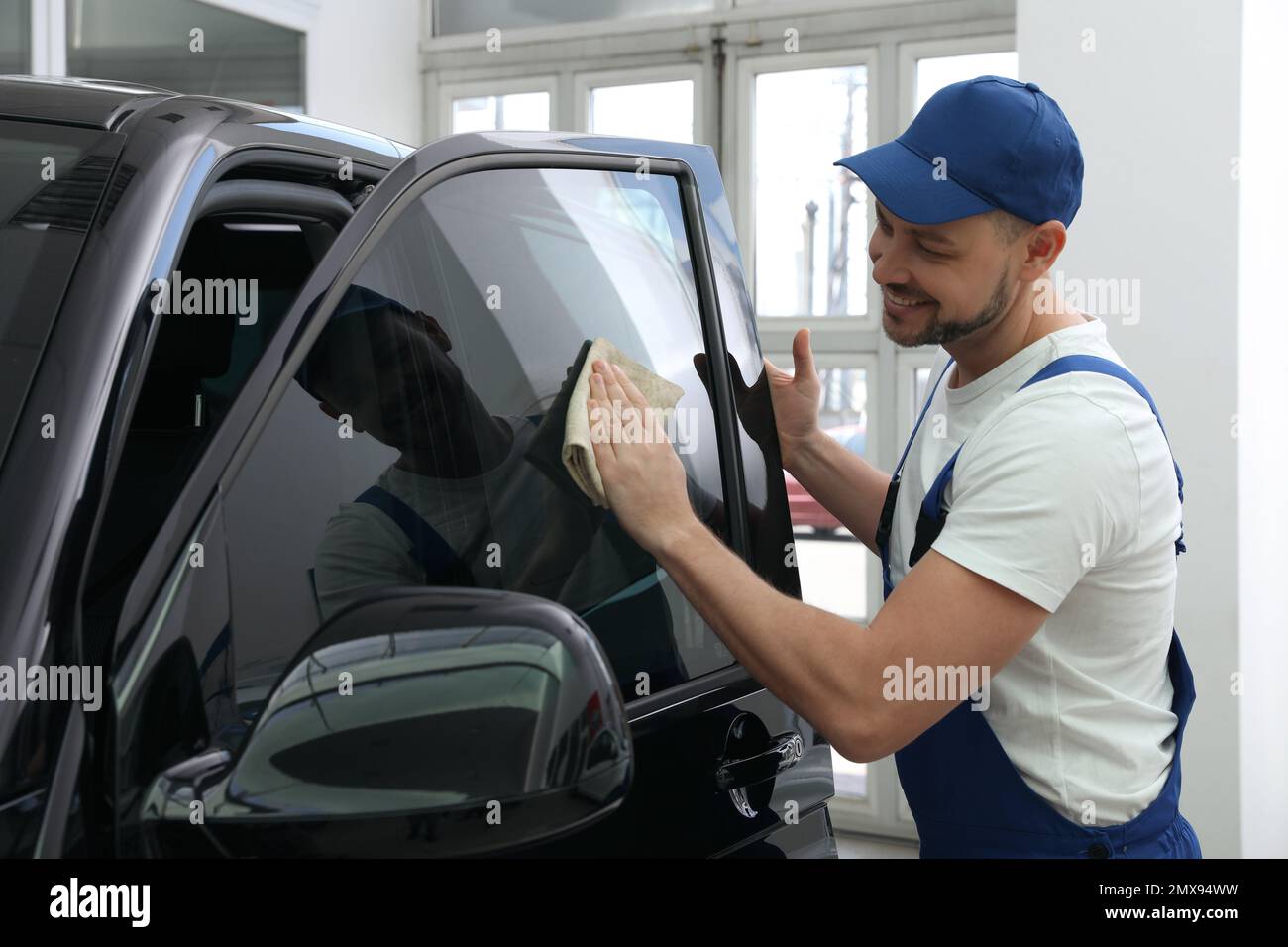 Worker tinting car window with foil in workshop Stock Photo - Alamy