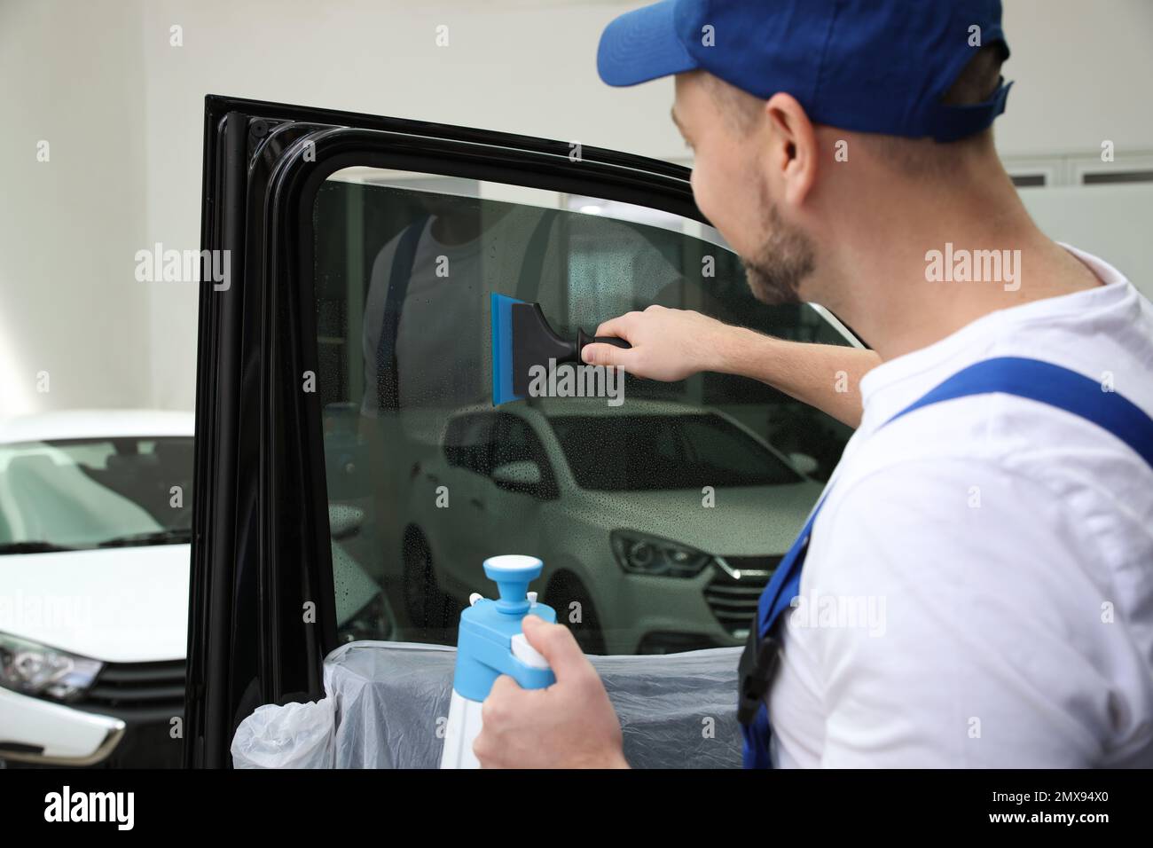 Worker washing tinted car window in workshop Stock Photo - Alamy