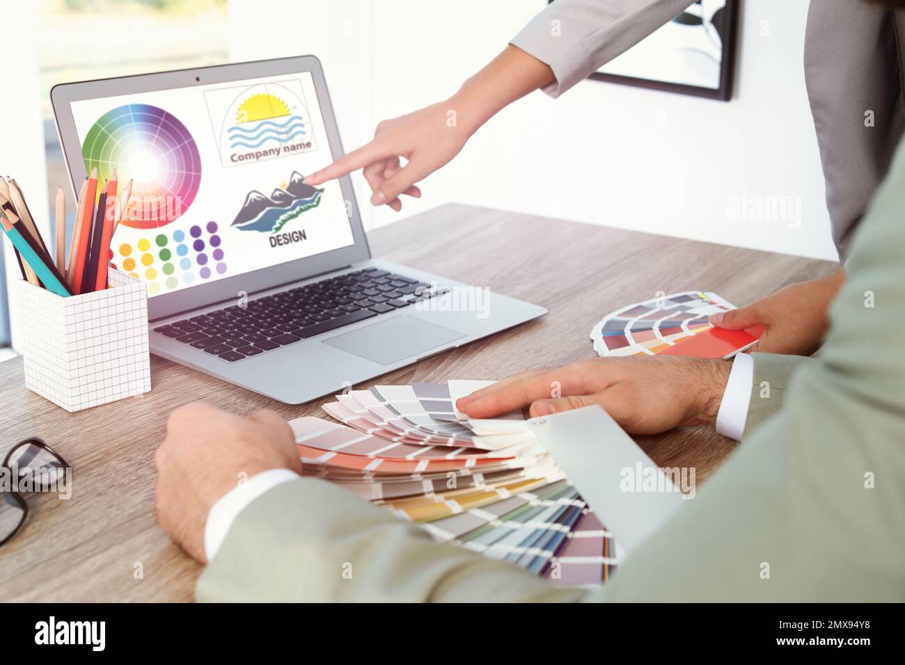 Professional designers working with color palette samples at desk at ...