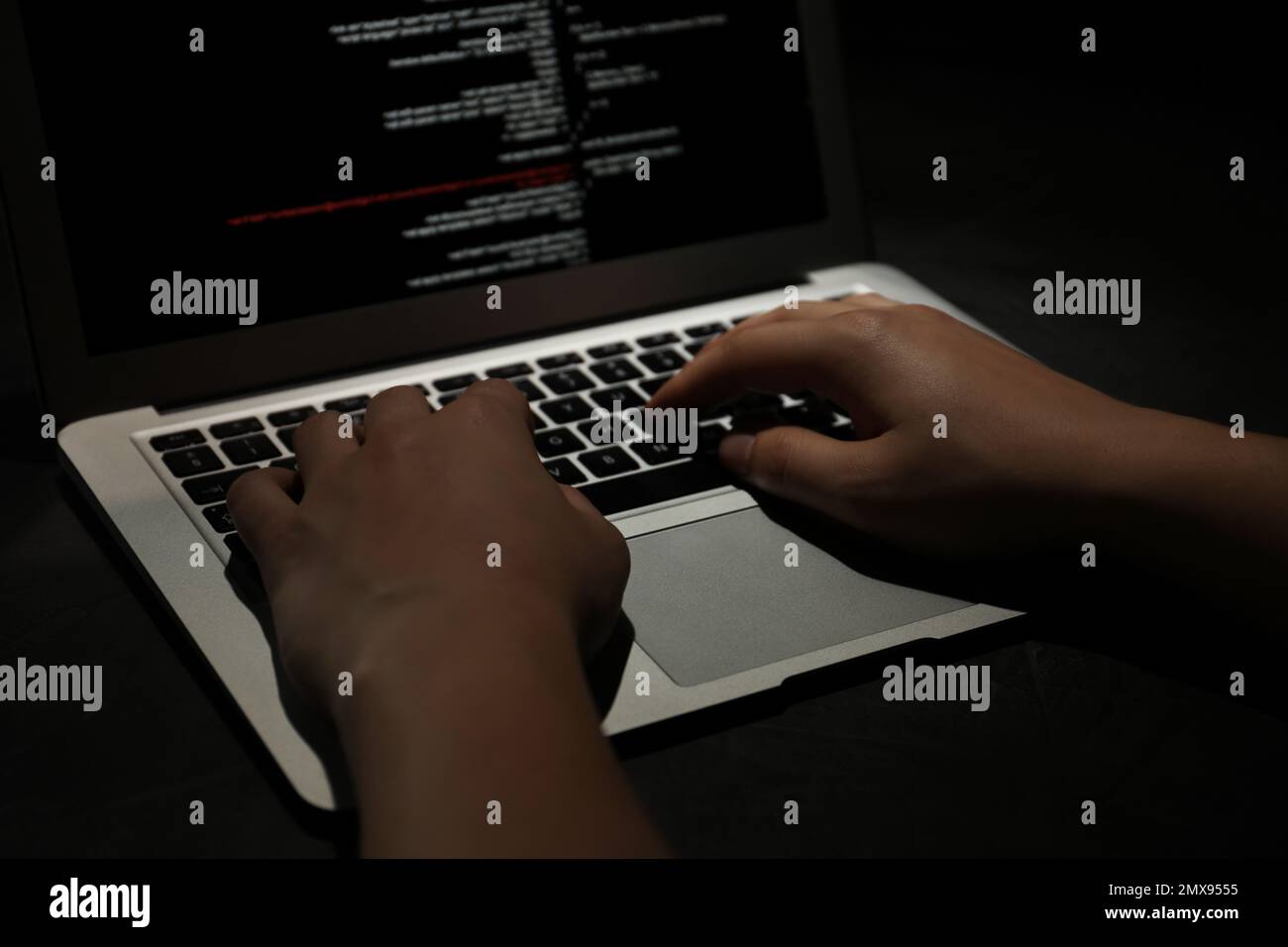 Hacker working with laptop in darkness, closeup of hands. Cyber crime ...