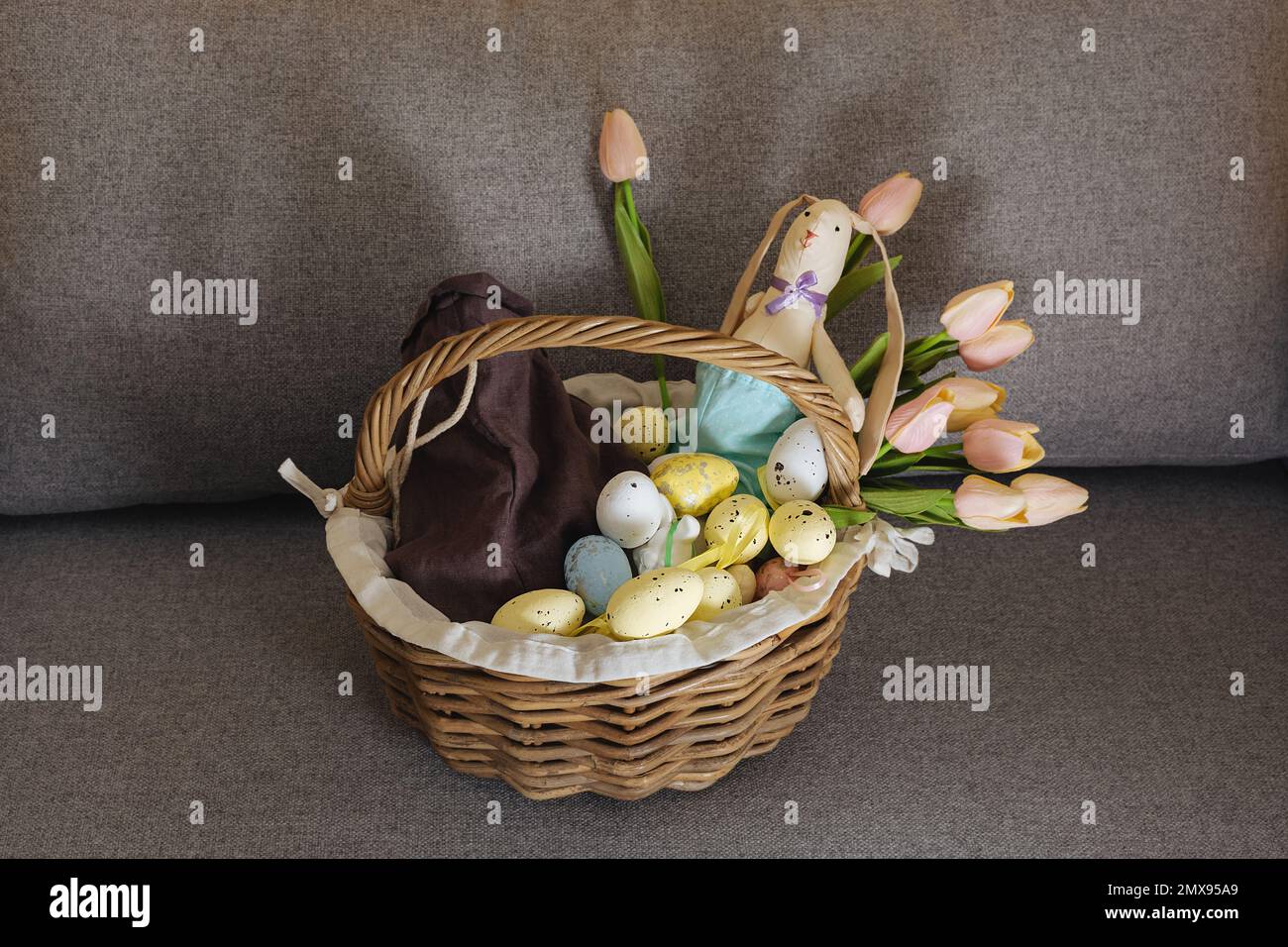 Happy Easter. Basket with colorful easter eggs, toy bunny, tulips and ...