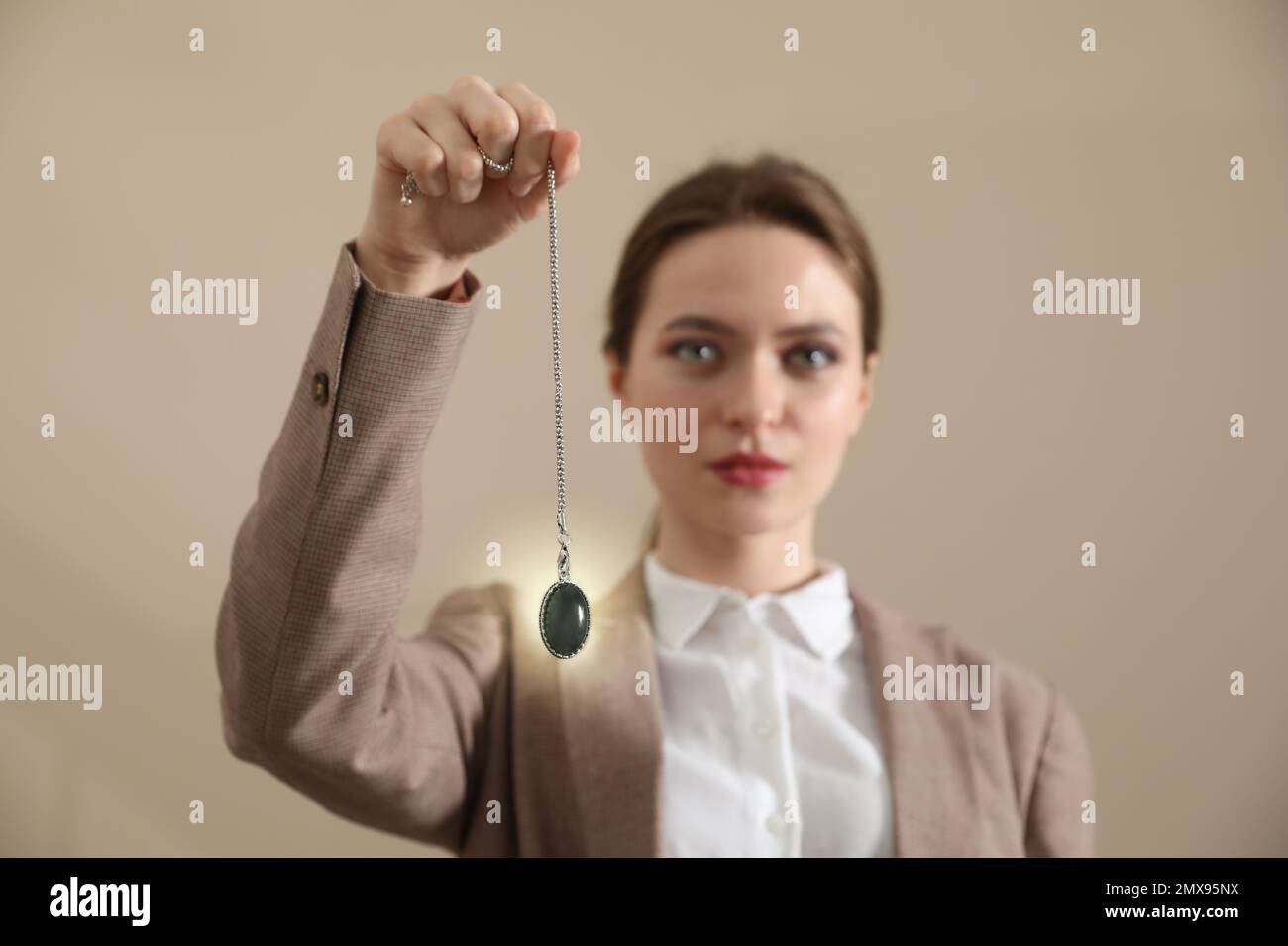 Psychotherapist with pendulum on beige background. Hypnotherapy session ...