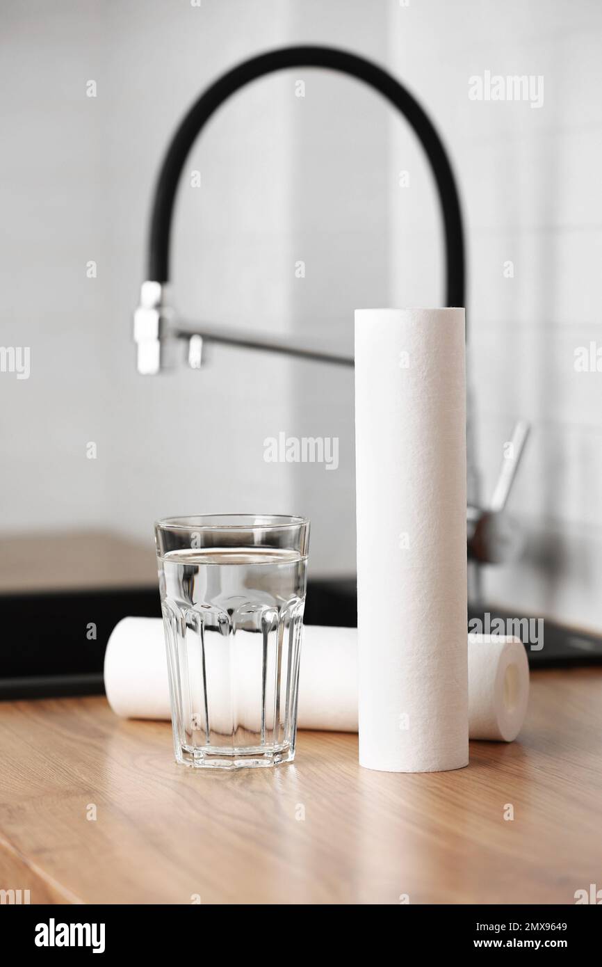 A glass of clean water and foamed polypropylene filter cartridges on ...