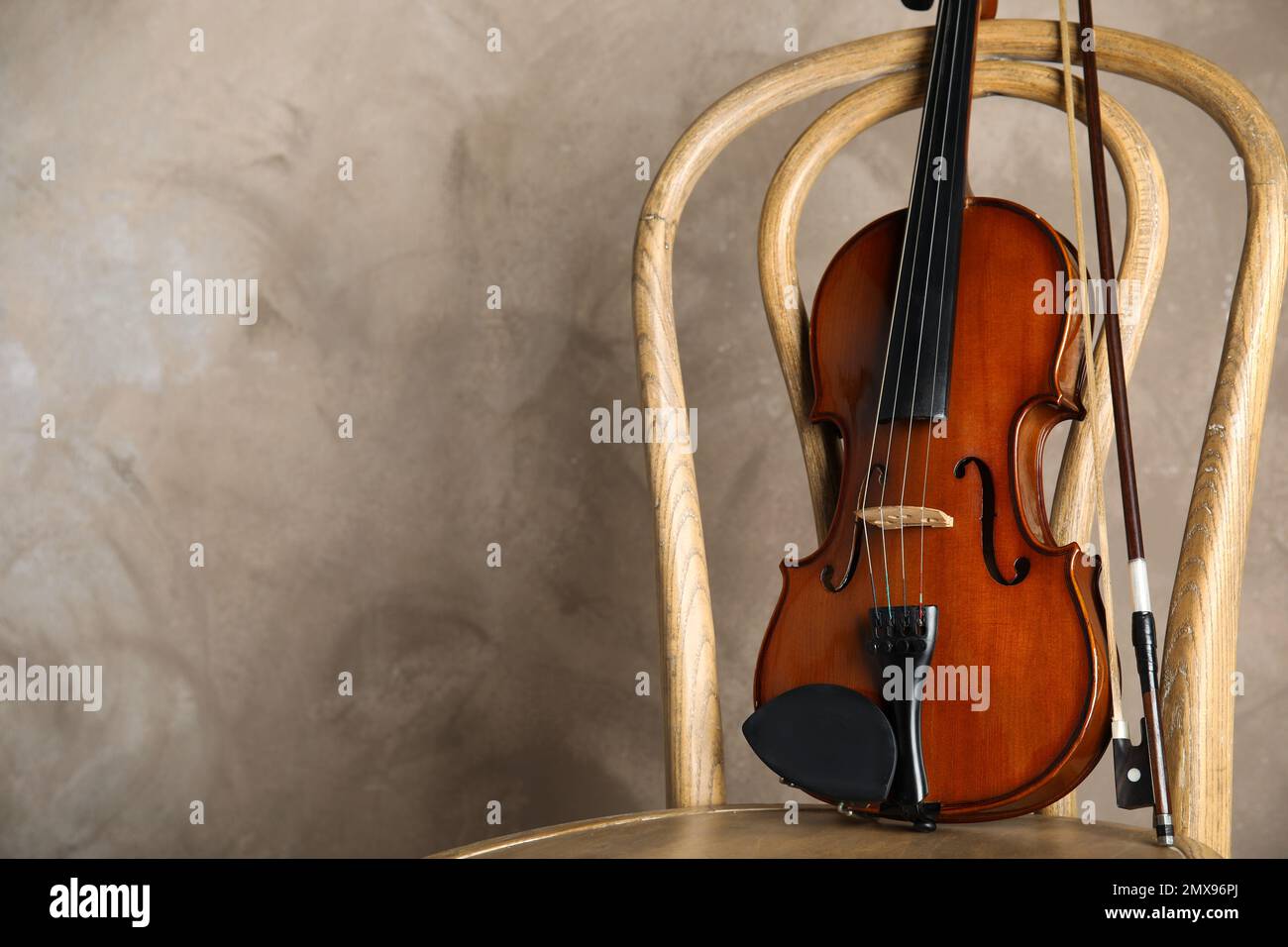 Classic violin and bow on chair against beige background. Space for ...
