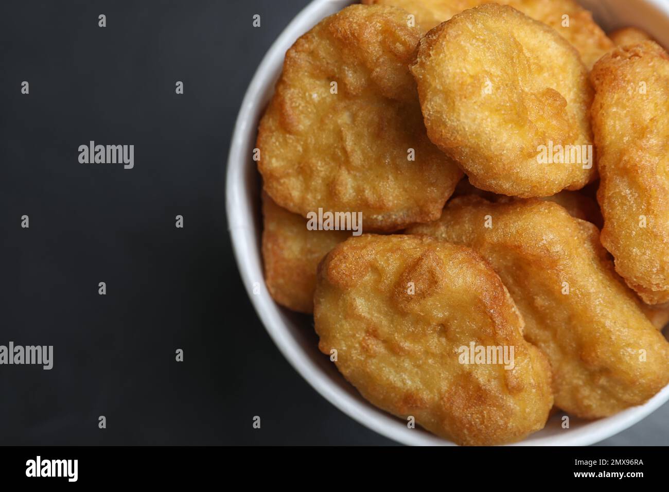 Bucket with tasty chicken nuggets on black table, top view Stock Photo ...